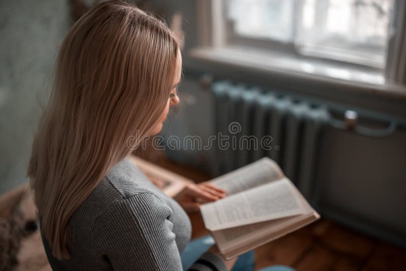 The Girl is Sitting at the Table and Reading a Book Stock Photo - Image ...