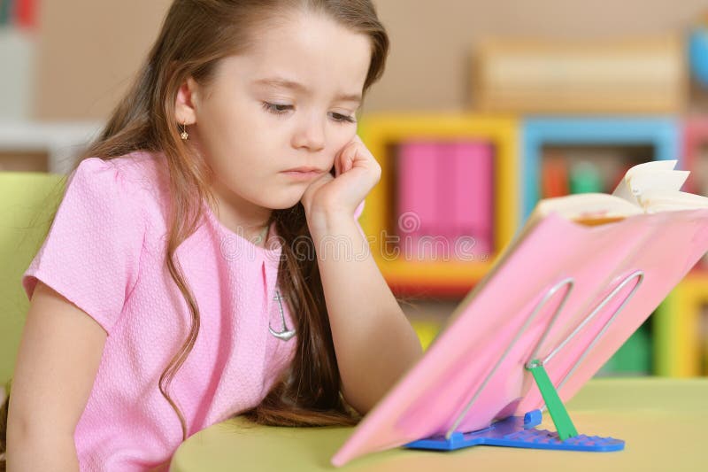 Girl is Sitting at the Table and Reading a Book Stock Photo - Image of ...