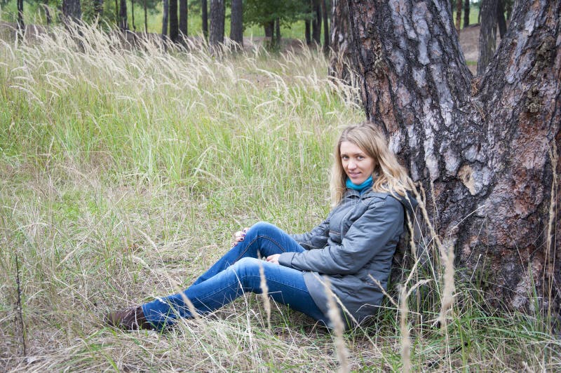 Girl Sitting in Tall Grass Near a Pine Tree. Stock Photo - Image of ...