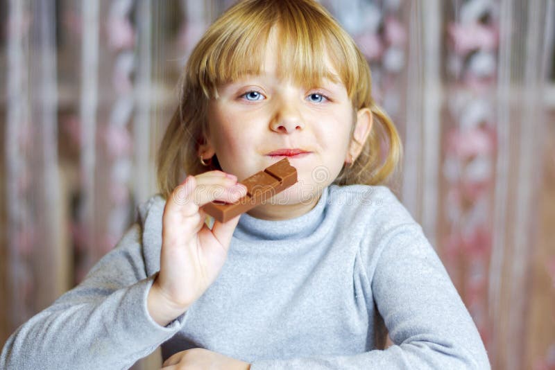 A Girl with a Smile on Her Face is Eating a Chocolate Bar Stock Image ...