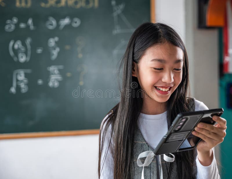 A Girl is Smiling while Holding a Cell Phone in Front of a Blackboard ...