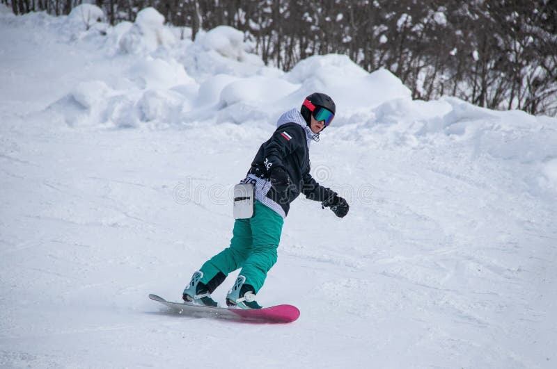 A Girl on a Snowboard Rides Down the Side of the Mountain Stock Photo ...