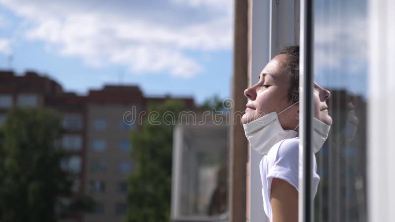Girl Stands On The Balcony Takes Off The Mask And Breathes Stock