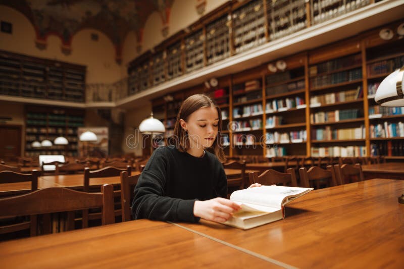 Girl Student in Dark Clothes Studies at Home with a Book on the Table ...