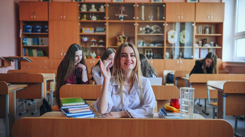 A Girl Student Sitting at a Desk Raises Her Hand in the Class. Stock ...