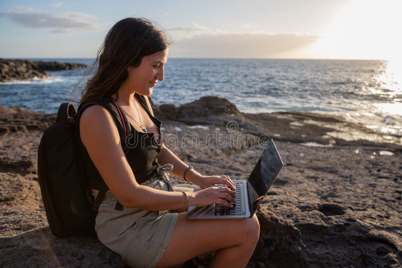 Girl Using Her Computer at the Sea, Working Remotely while Travelling ...