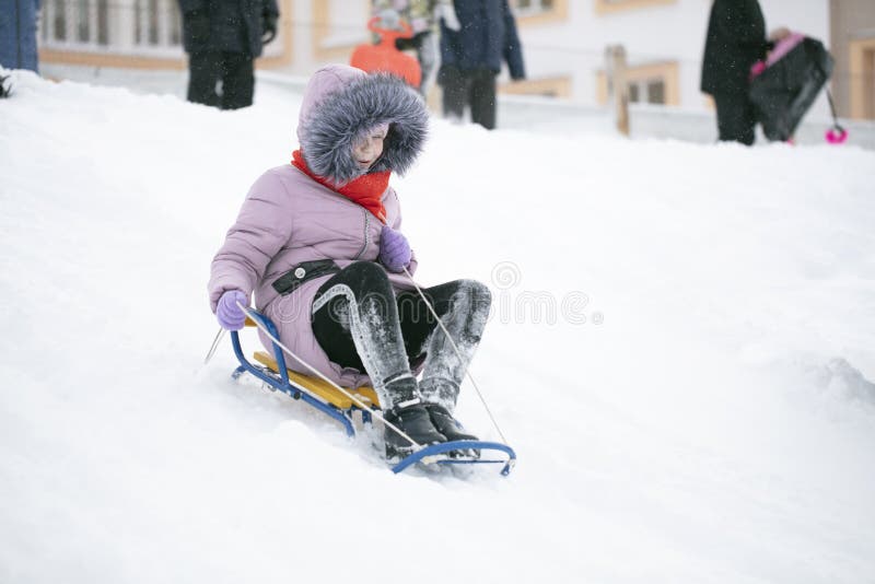 A Girl Warmly Dressed Sledding Stock Image - Image of candid, cold ...