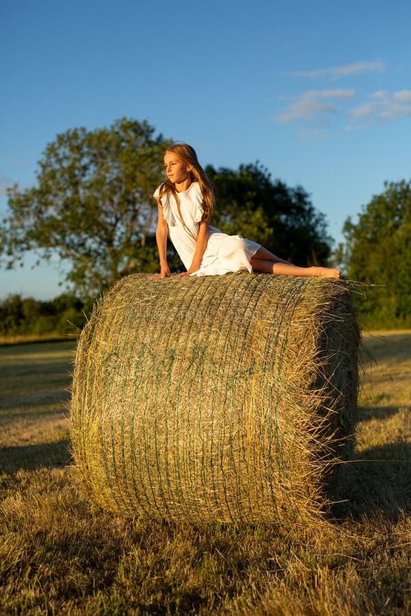 A Girl in White Cloth on a Round Haystack in the Field Stock Photo ...