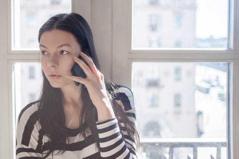 Girl at the Window Talking on the Phone at Home in Morning Sunlight ...