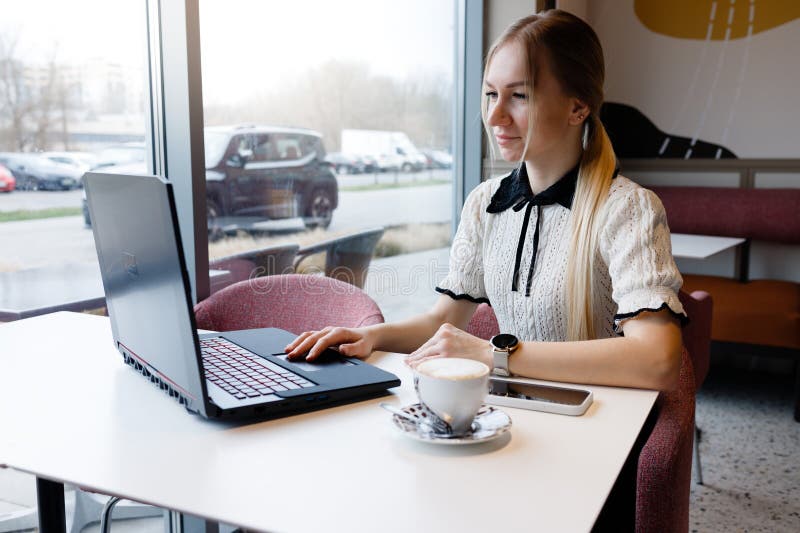 A Girl Works at a Computer in a Coffee Shop. Stock Image - Image of ...