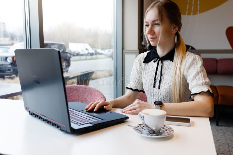 A Girl Works at a Computer in a Coffee Shop. Stock Photo - Image of ...