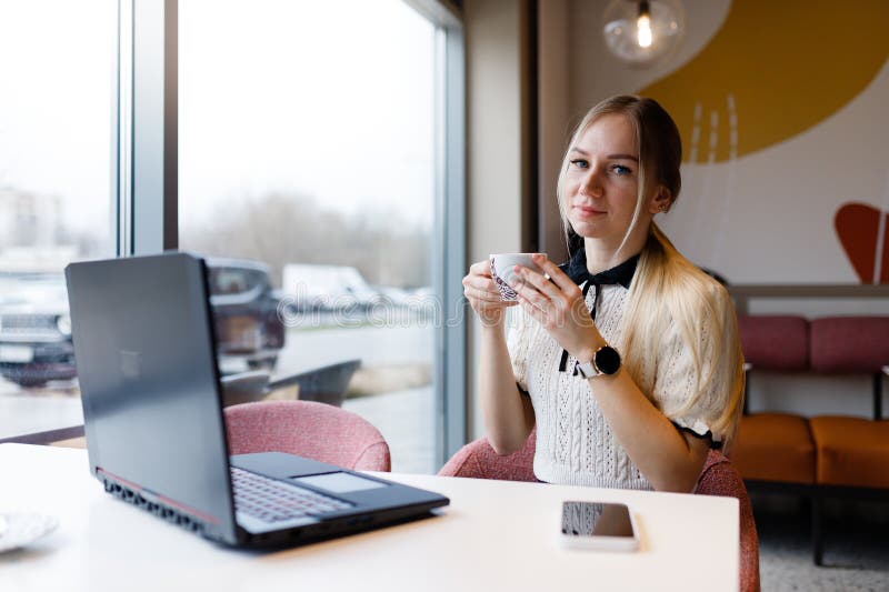 A Girl Works at a Computer in a Coffee Shop. Stock Photo - Image of ...