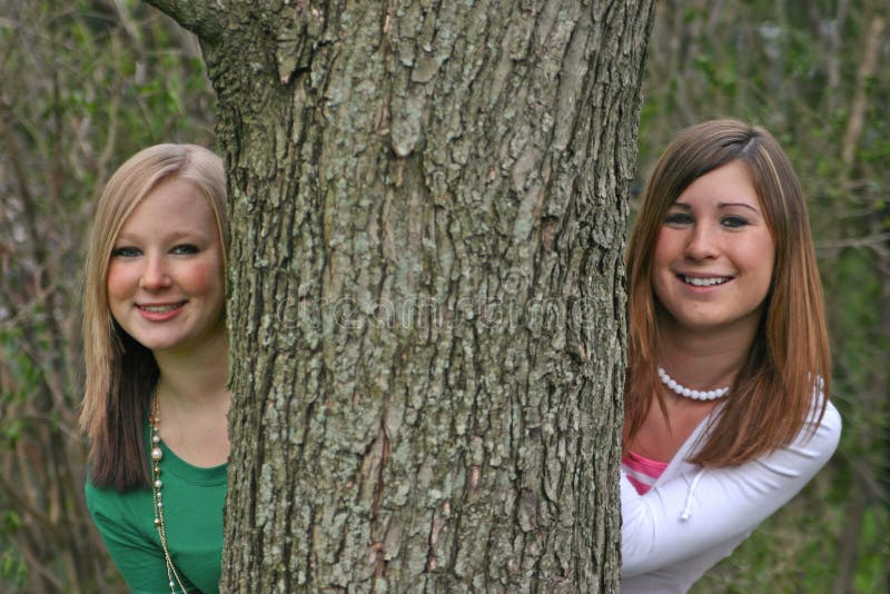 Girls Peeking Around A Tree Stock Photo - Image of buddies, adolescence ...