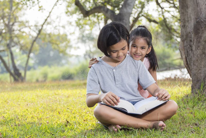 Girls sit and reading. Girls sit and read a book in the park.