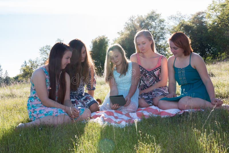Girls Sitting Together in Grassy Field with Sunlight Overhead Stock ...