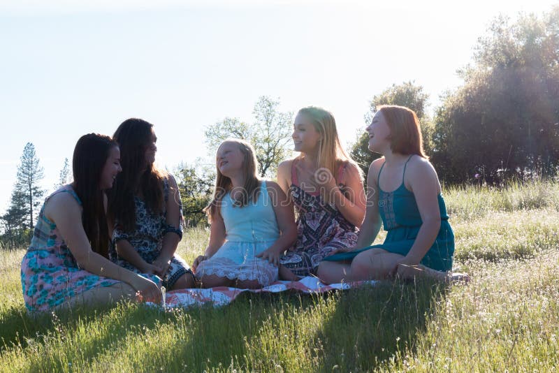 Girls Sitting Together in Grassy Field with Sunlight Overhead Stock ...