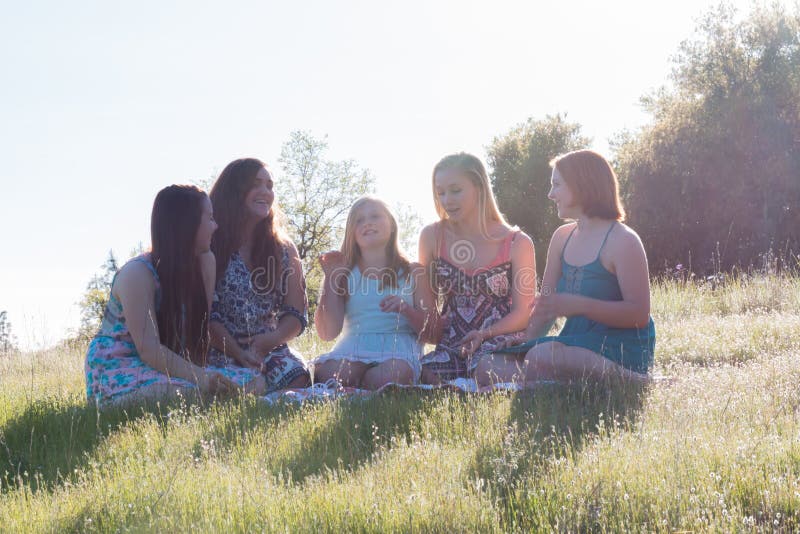 Girls Sitting Together in Grassy Field with Sunlight Overhead Stock ...