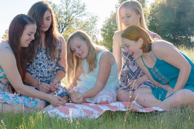 Girls Sitting Together in Grassy Field with Sunlight Overhead Stock ...