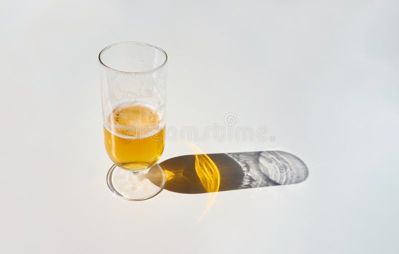 Glass of Beer with Shadow Reflected on White Table and with Sun Shine ...