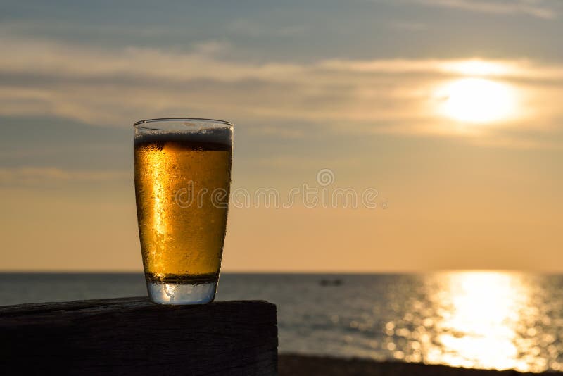 Glass of beer on a sunset stock image. Image of sand - 85585291