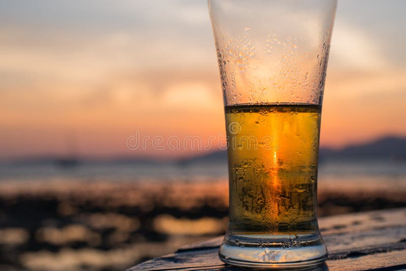 Glass of beer on a sunset stock image. Image of sand - 85585291