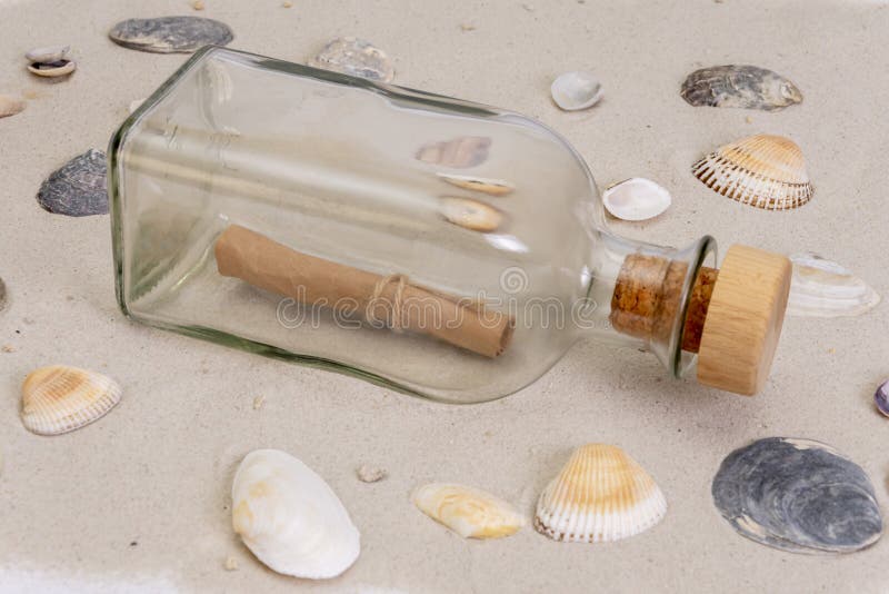 A Glass Bottle with a Note Inside on a Sandy Beach with Shells . a ...
