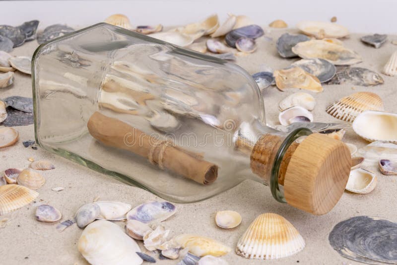 A Glass Bottle with a Note Inside on a Sandy Beach with Shells . a ...