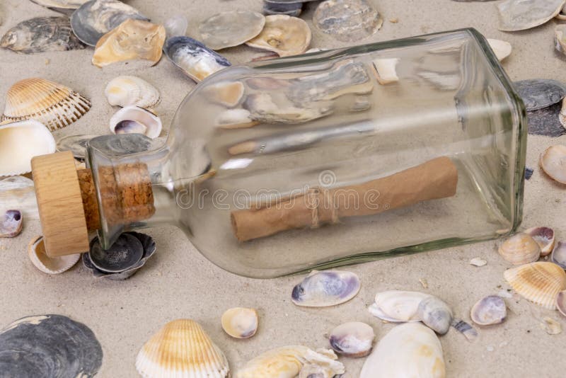 A Glass Bottle with a Note Inside on a Sandy Beach with Shells . a ...