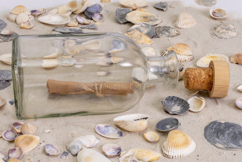 A Glass Bottle with a Note Inside on a Sandy Beach with Shells, an Open ...