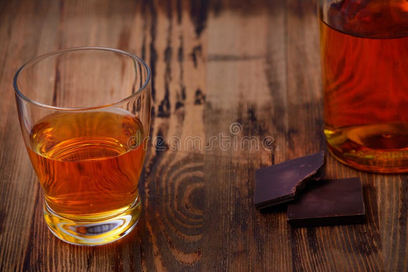 Glass of Brandy Chocolate Pieces, a Bottle on a Wooden Table Stock ...