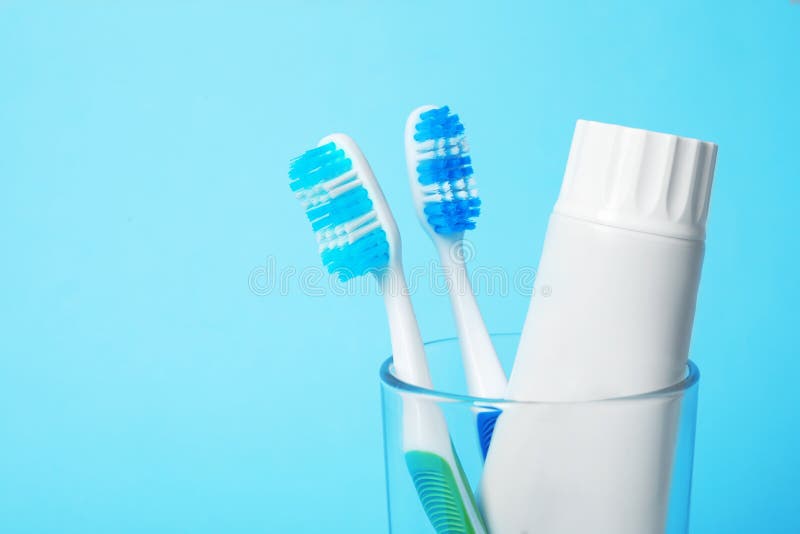 Glass with Brushes and Toothpaste on Color Background Stock Photo ...
