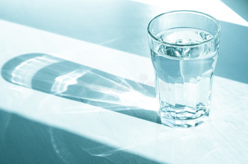 A Glass with Clean Clear Water and Sharp Shadows Stands on a White ...
