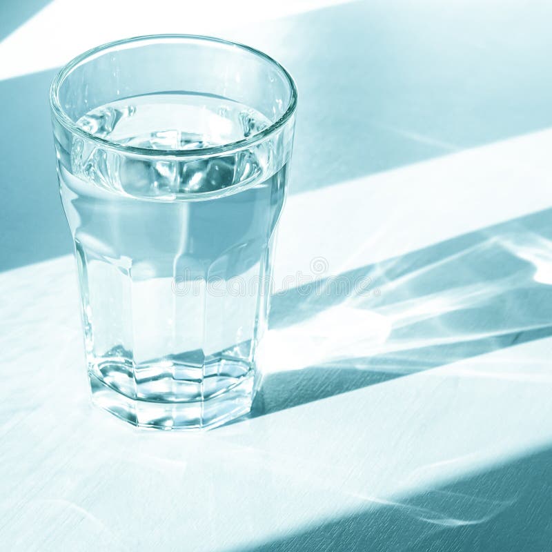 A Glass with Clean Clear Water and Sharp Shadows Stands on a White ...