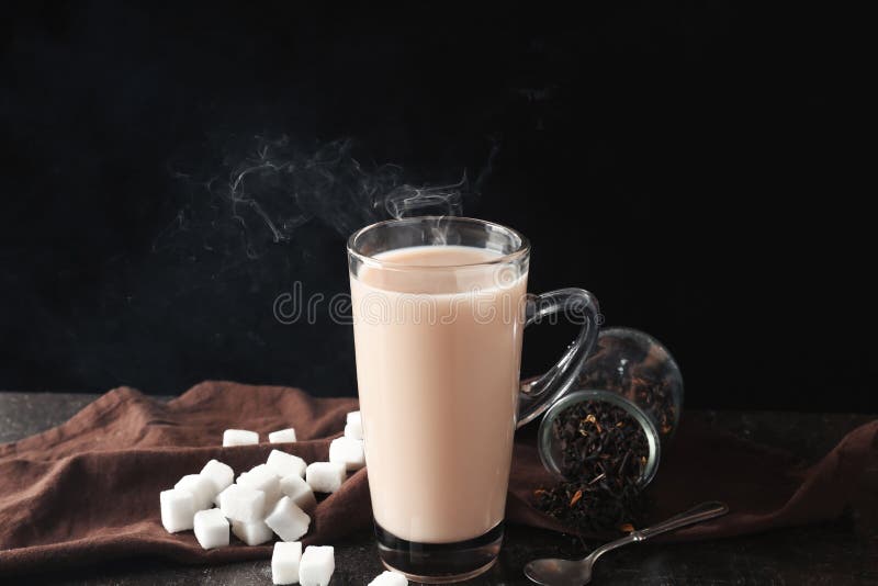 Glass Cup with Aromatic Tea and Milk on Table Against Dark Background ...