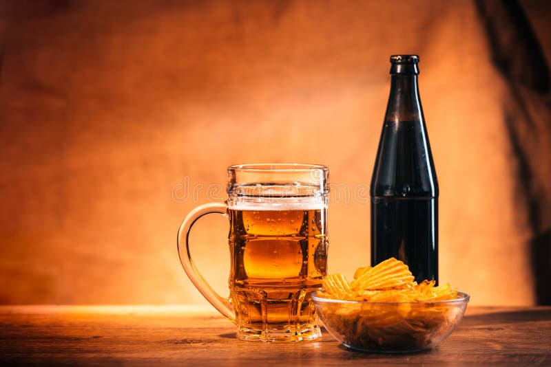Glass of Fresh Light Beer, a Bottle Beer and Chips on a Wooden Table ...