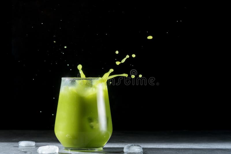 A Glass of Green Cocktail with Ice and Splash on a Dark Background ...