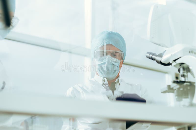 Through the Glass. Group of Scientists in Protective Masks Work in the ...