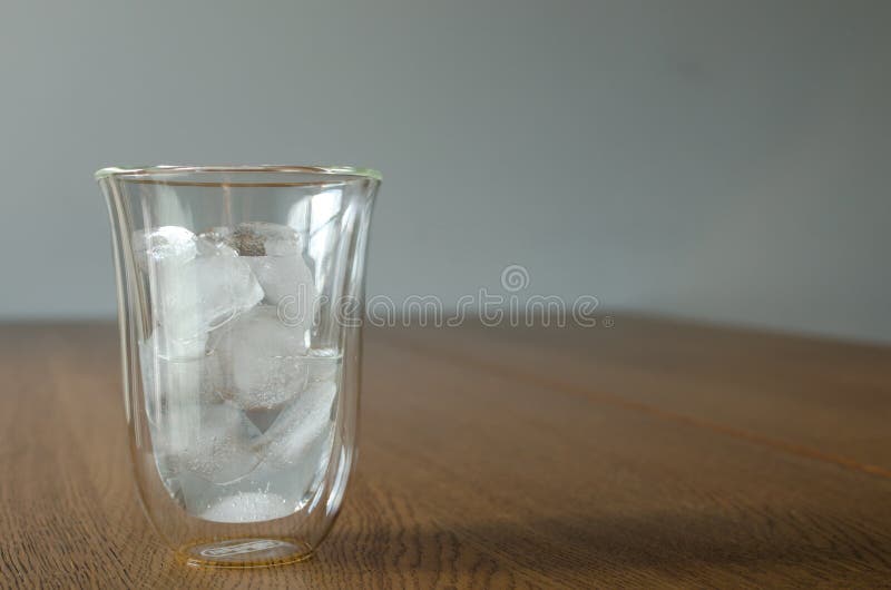 Glass with Half Melting Ice Pieces on the Wooden Table. Ice is ...