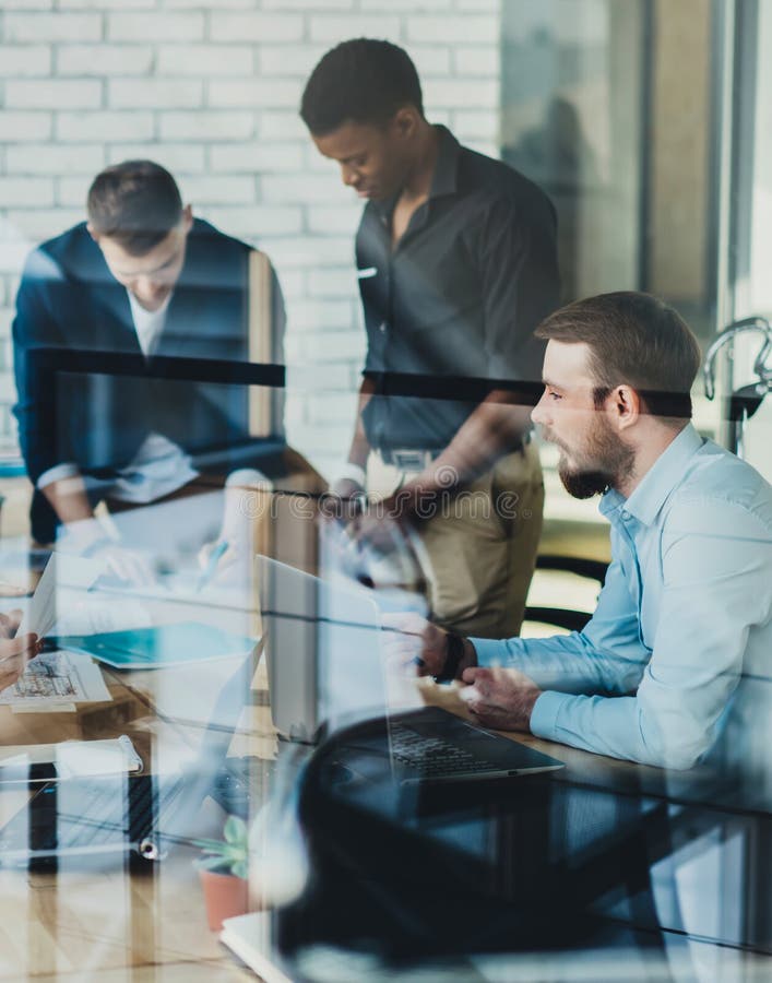 Diligent Adult Diverse Colleagues Examining Reports during Meeting in ...