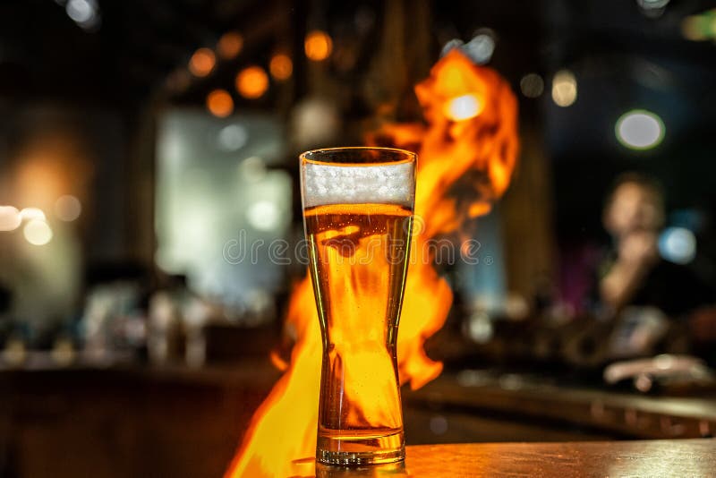 A Glass of Light Lager Beer on a Background of a Burning Flame. Amber ...