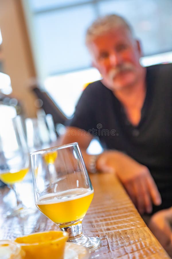 Glass of Micro Brew Beer on Bar with Handsome Man in Background. Stock ...