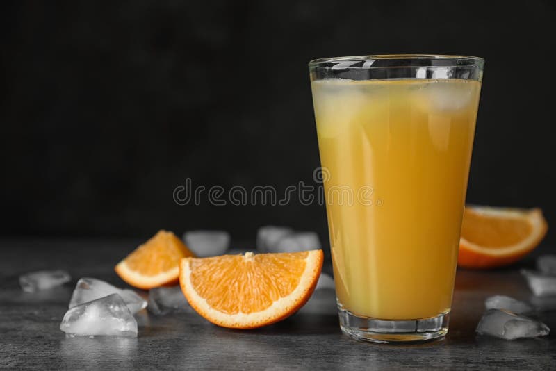 Glass of Orange Juice with Ice Cubes and Cut Fruit on Table Against ...
