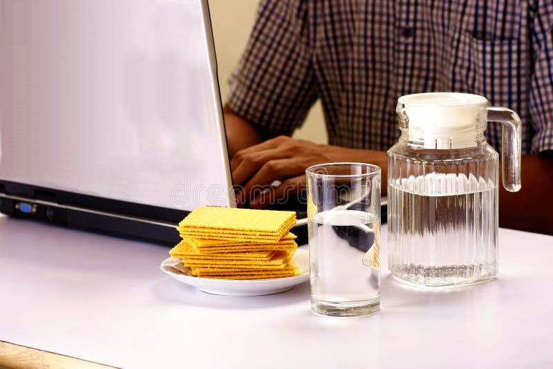 Glass and Pitcher of Water and a Stack of Crackers and Man Working on a ...