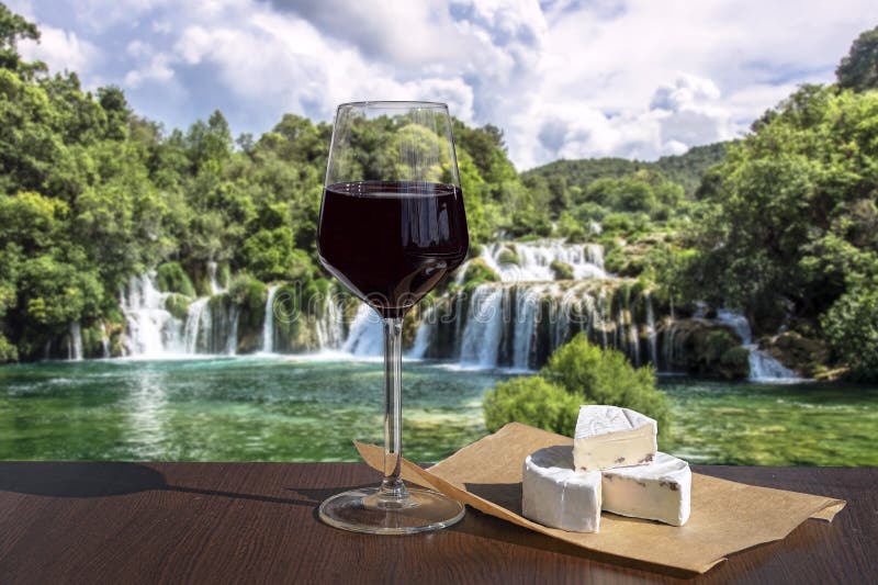 Glass of Red Wine with Cheese Snacks Against Waterfall Cascade in ...