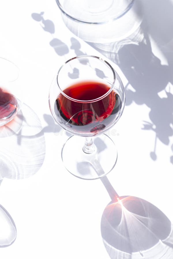 A Glass of Red Wine on the White Table with Leaves Shadows Modern ...