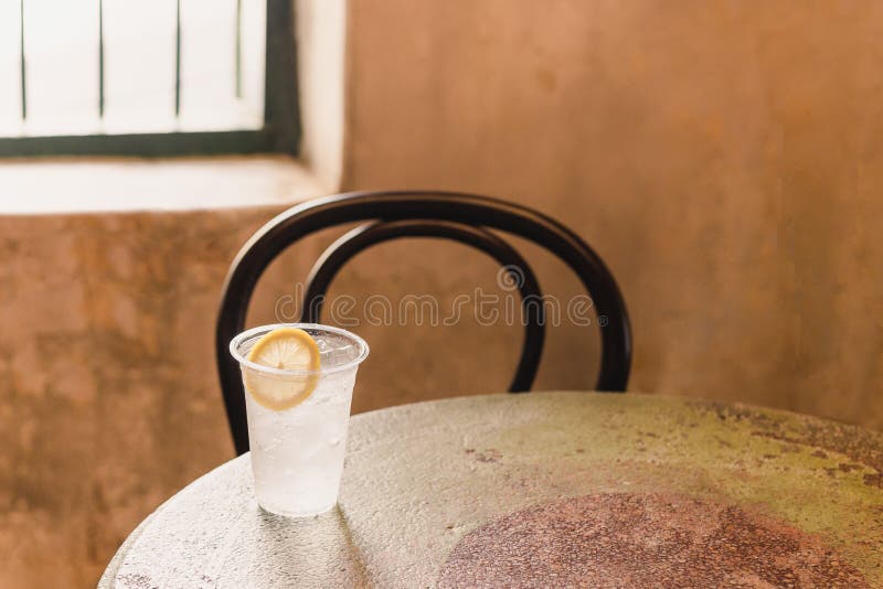 Glass of Sparkling Water with Slice of Lemon on Table with Chair. Stock ...