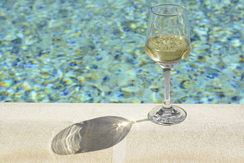 Glass of Tasty Wine on Swimming Pool Edge, Space for Text Stock Photo ...