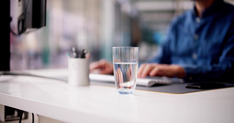 Glass of Water on Desk and Man in Background Stock Image - Image of ...