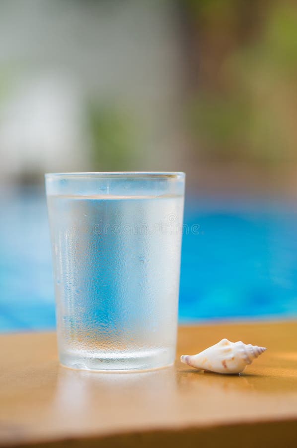 Glass of Water with Drops and Small Shells on Pool Side in Tropical ...