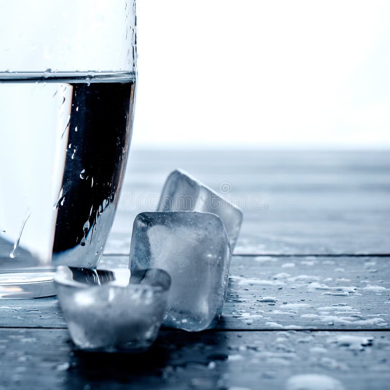 Glass of Water and Melting Ice Cubes on a Wooden Table. Stock Photo ...